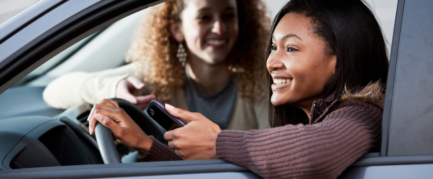 Teenage girls in car with mobile phone – AAA Exchange